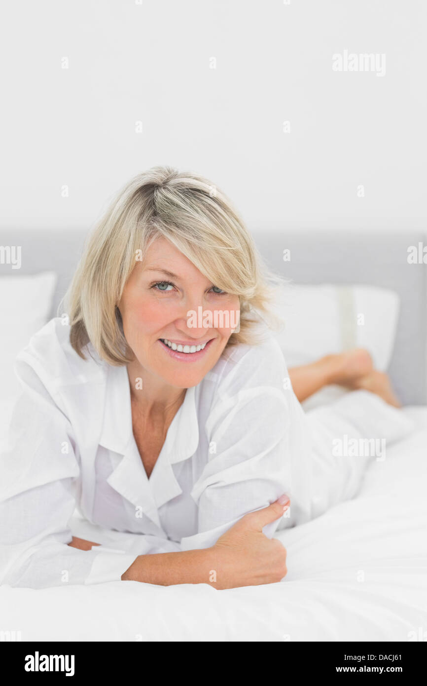 Happy woman lying on her bed Stock Photo - Alamy