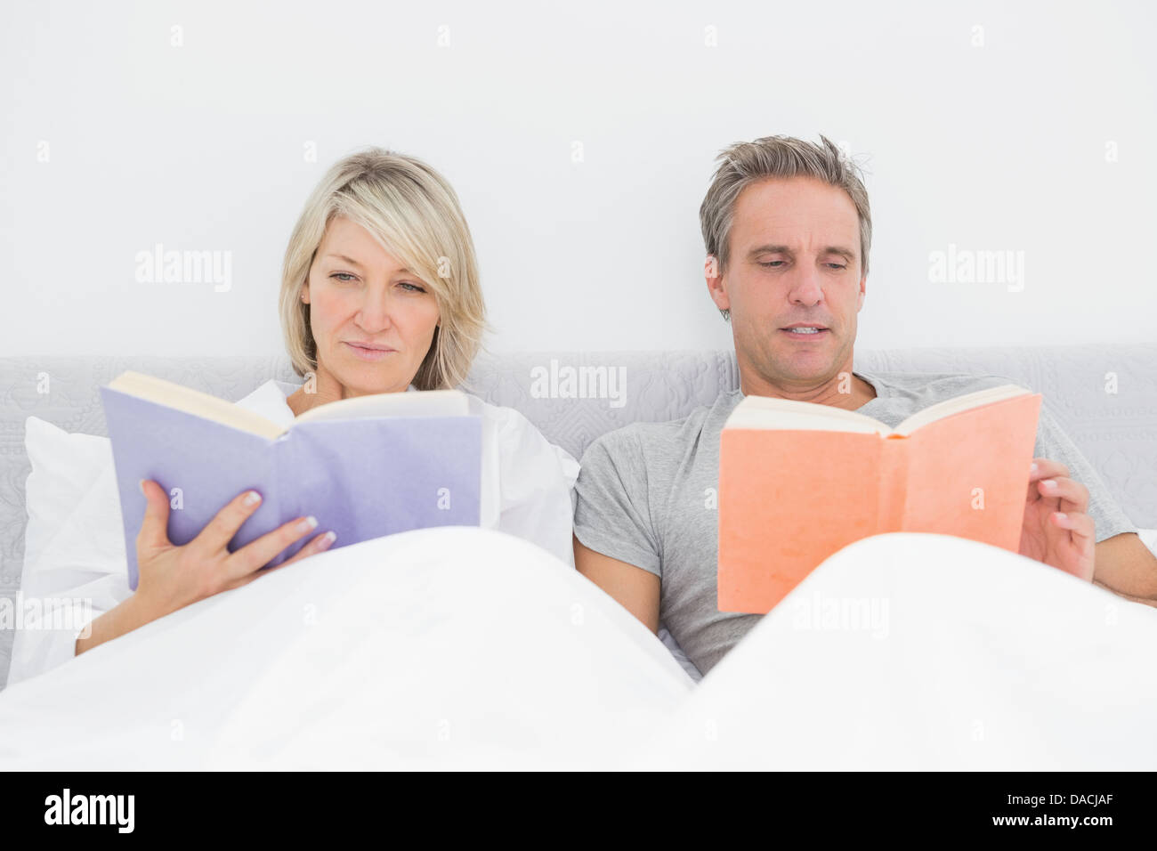 Relaxed couple reading in bed Stock Photo - Alamy