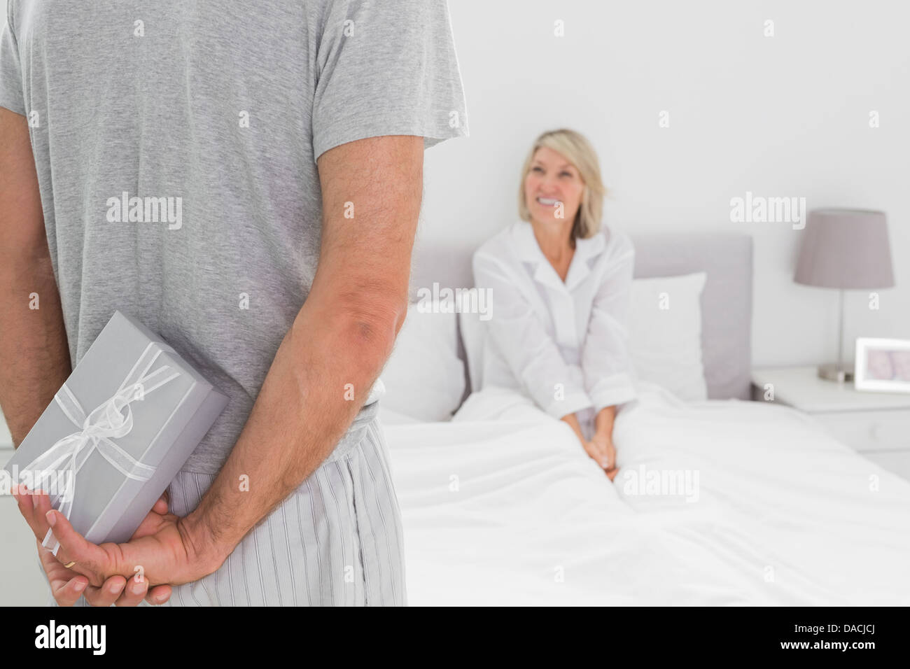 Man hiding present behind his back for partner Stock Photo - Alamy