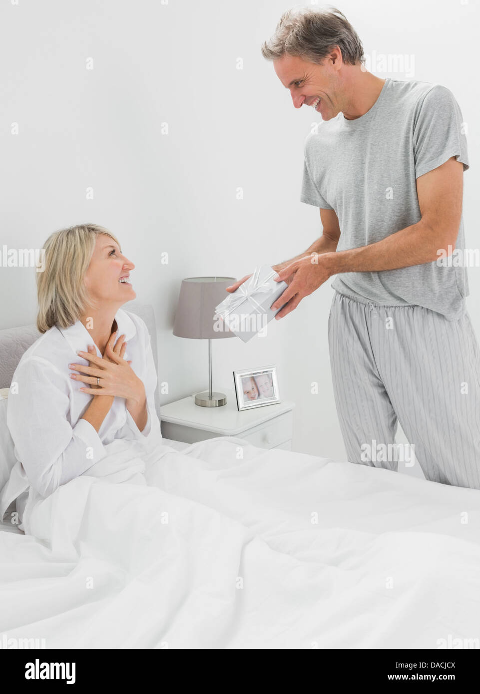 Man giving present to his surprised partner Stock Photo - Alamy