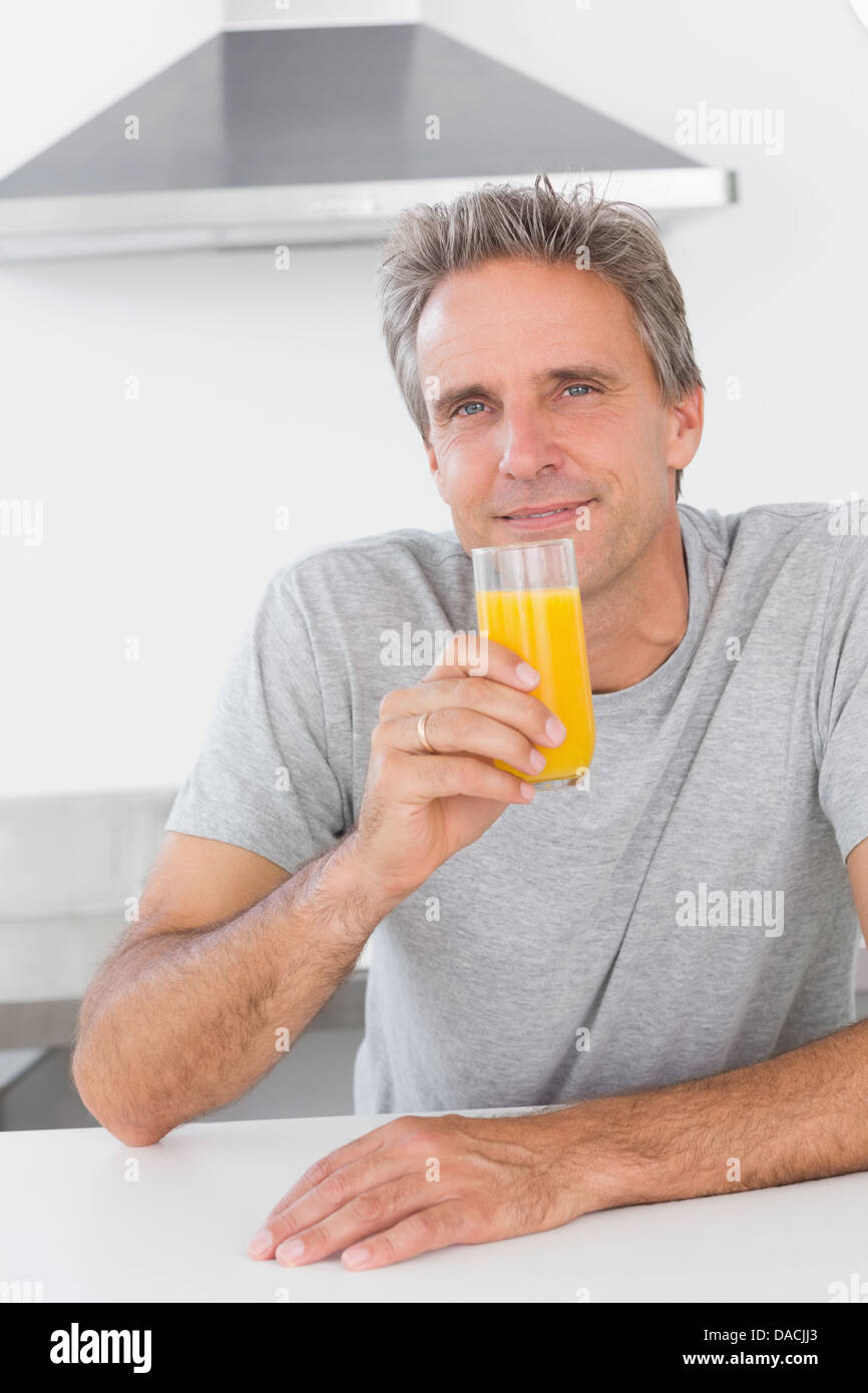 Cheerful man having glass of orange juice in kitchen Stock Photo - Alamy