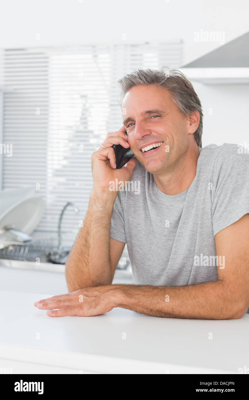 Laughing man making phone call in kitchen Stock Photo - Alamy