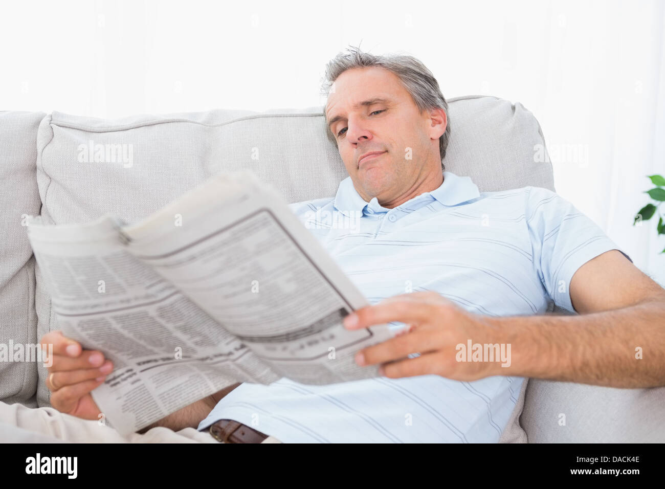 Man reading the newspaper on couch Stock Photo - Alamy