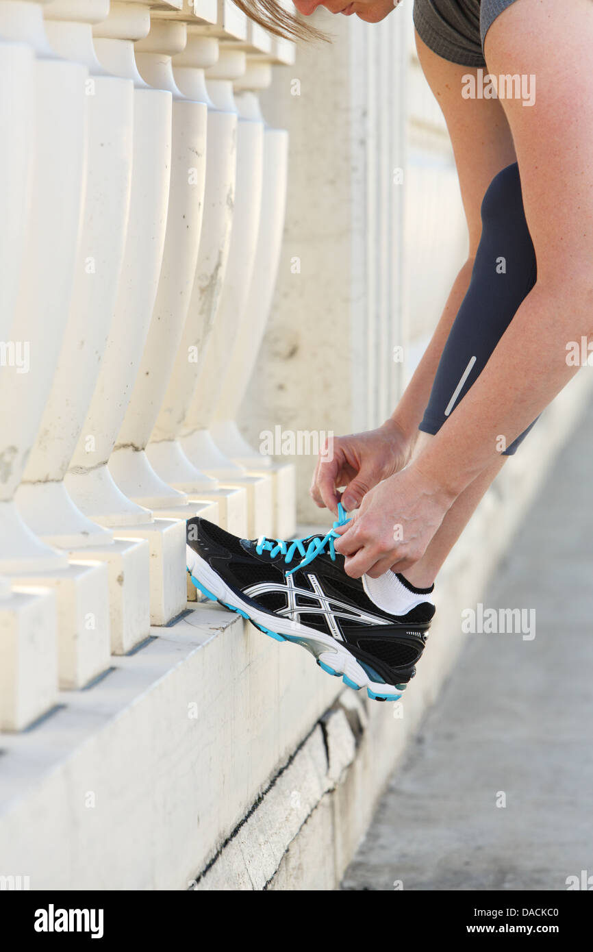 Female runner tying her shoe Stock Photo - Alamy
