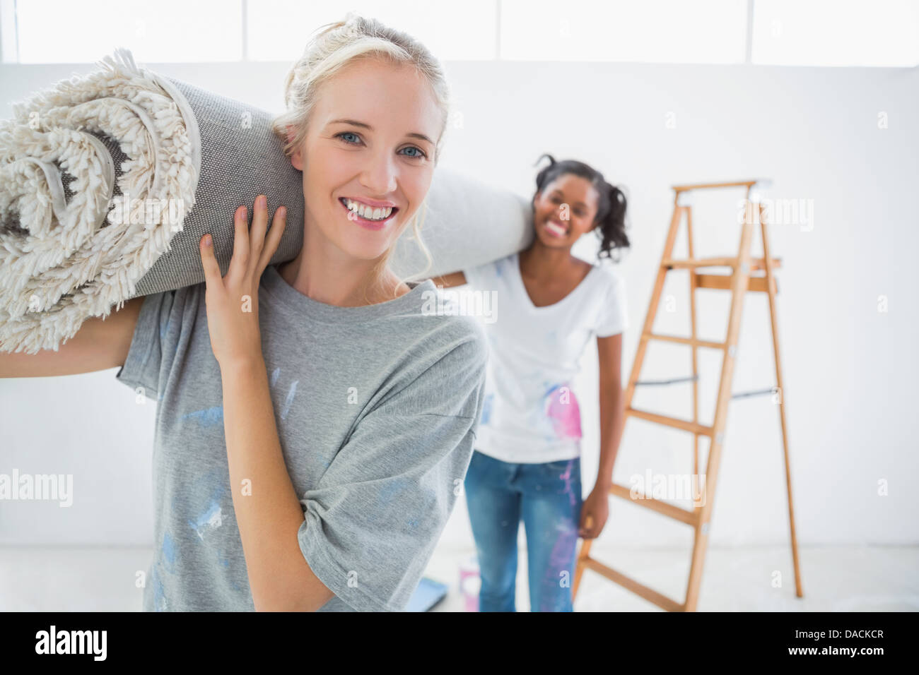 Happy housemates carrying rolled up rug in new home Stock Photo - Alamy