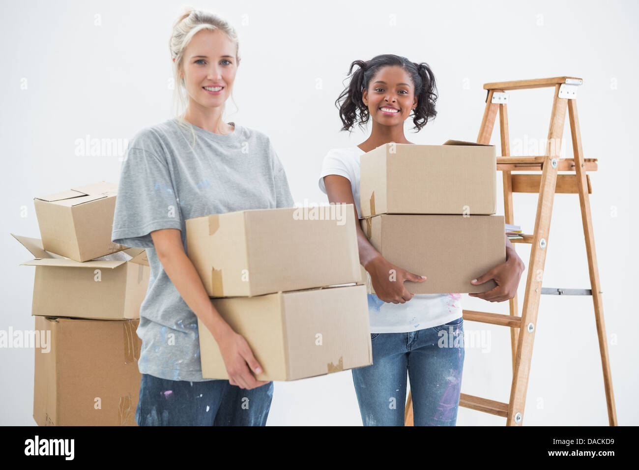 Happy housemates carrying moving boxes Stock Photo - Alamy