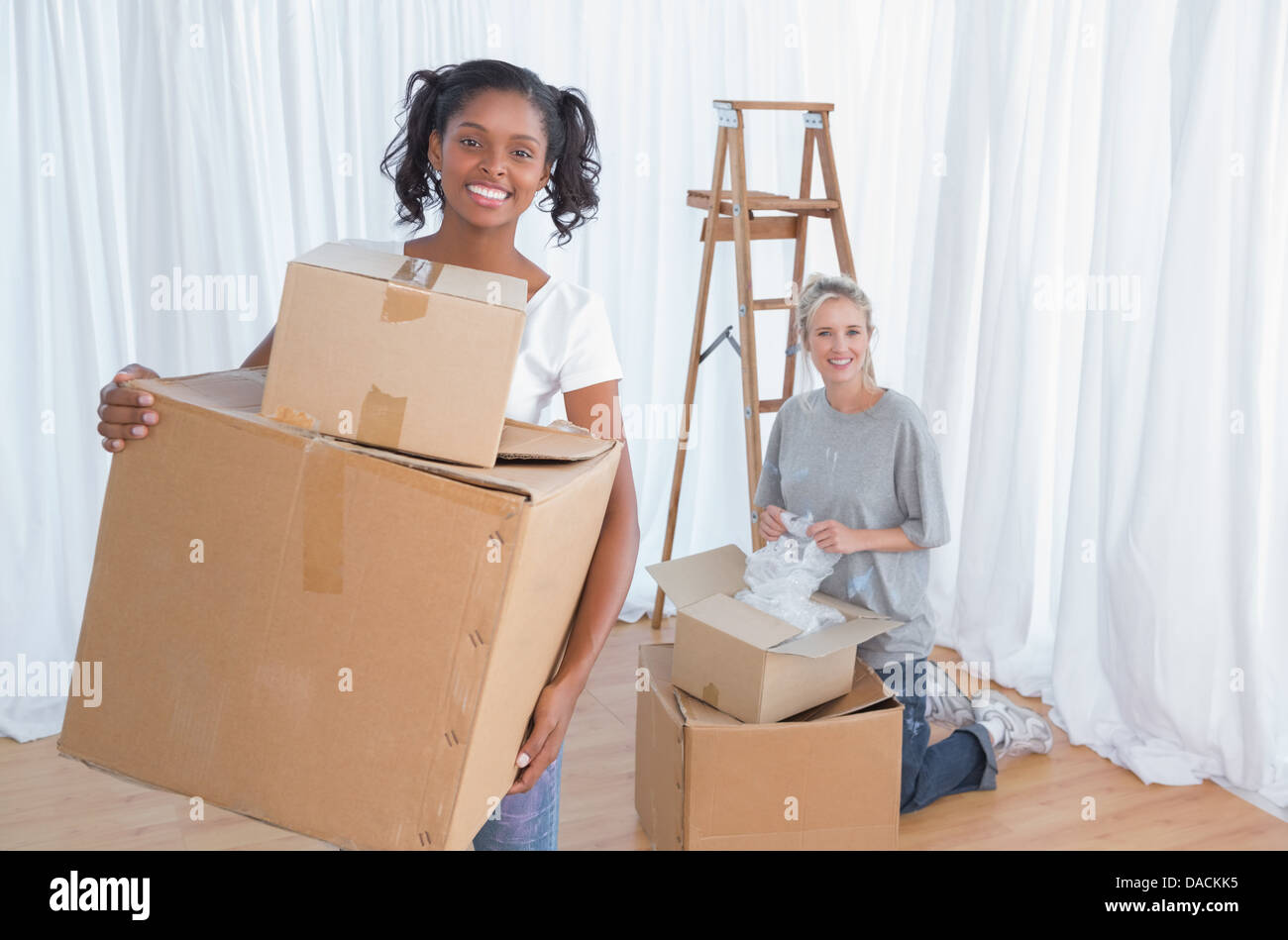 Young friends unpacking in their new home and smiling at camera Stock ...