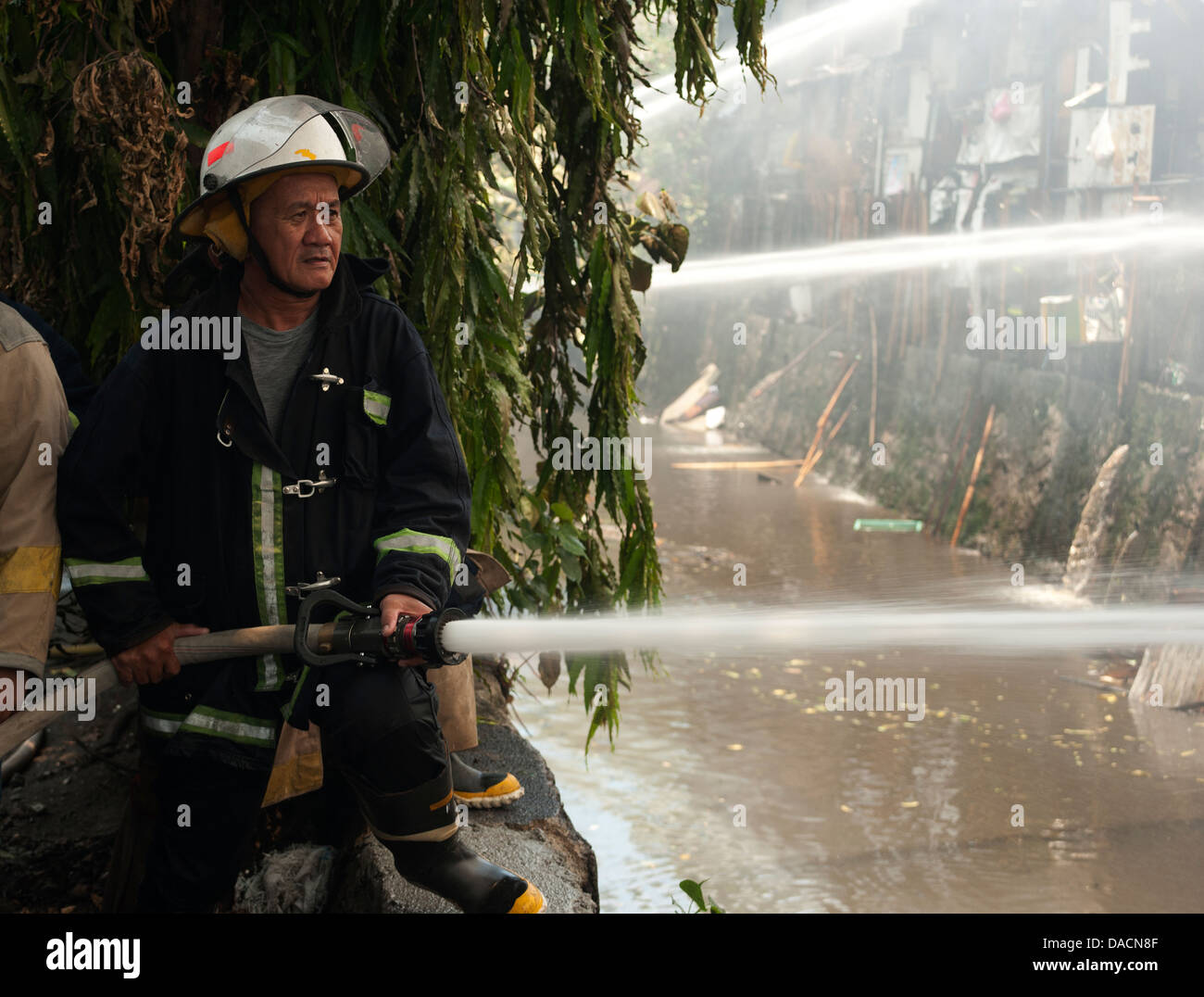 Firemen hose down a fire in a shanty town in Makati City, Metro Manila ...