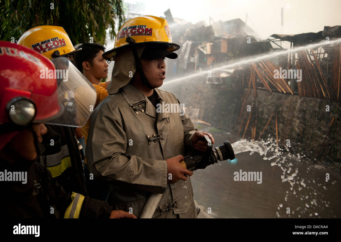 Firemen hose down a fire in a shanty town in Makati City, Metro Manila ...