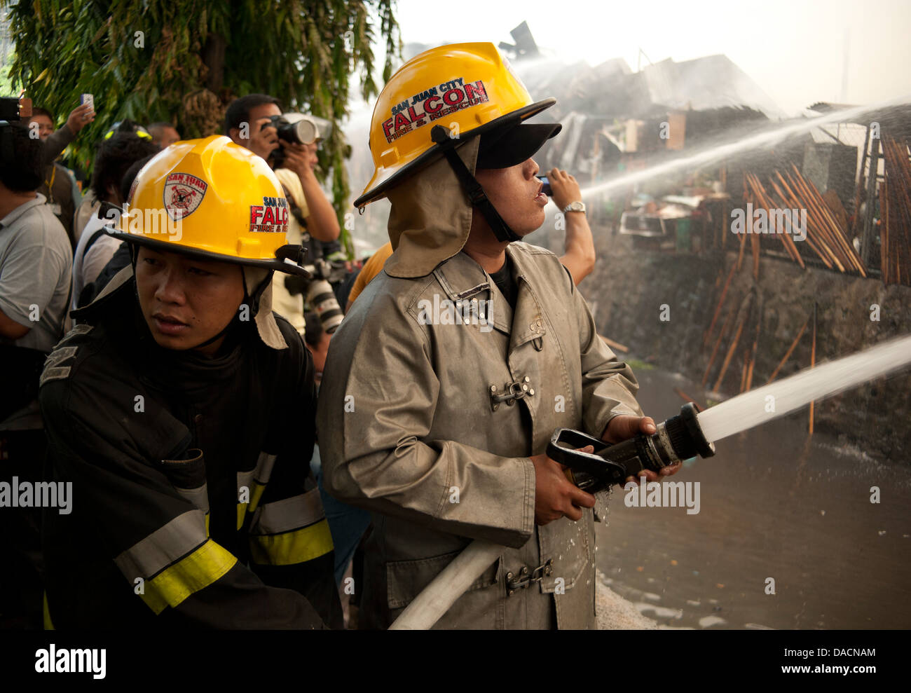 Firemen hose down a fire in a shanty town in Makati City, Metro Manila ...