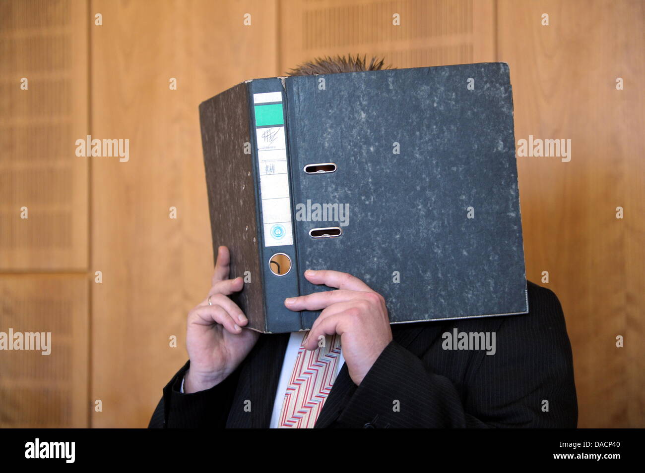 Olaf H., charged with murder, holds a folder in front of his face ...