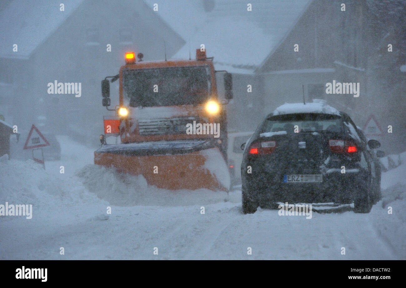 Heavy snow drifts and snow plow cause traffic problems on a street near ...