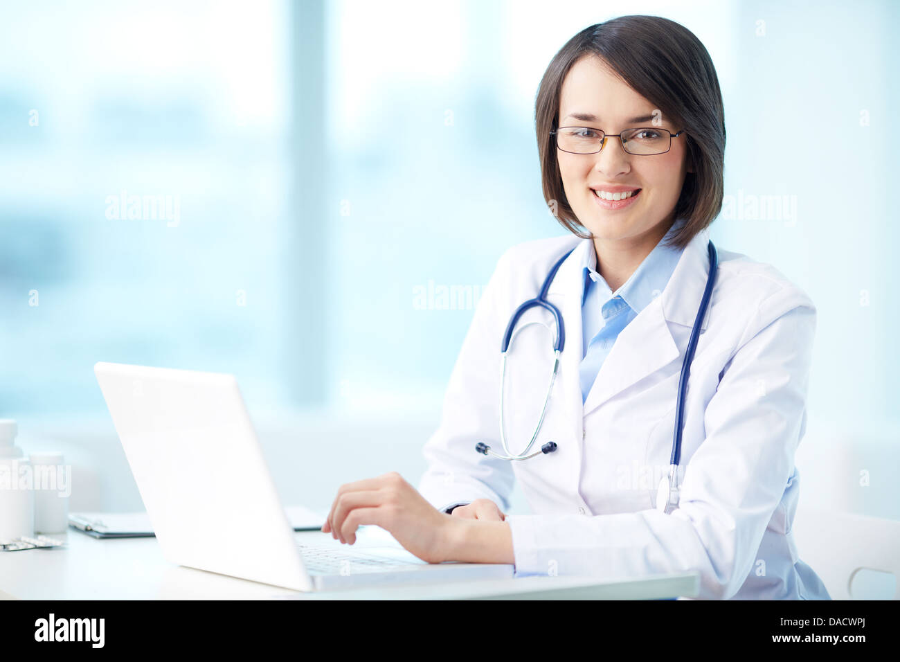 Portrait of a smiling physician being busy with computer work Stock ...