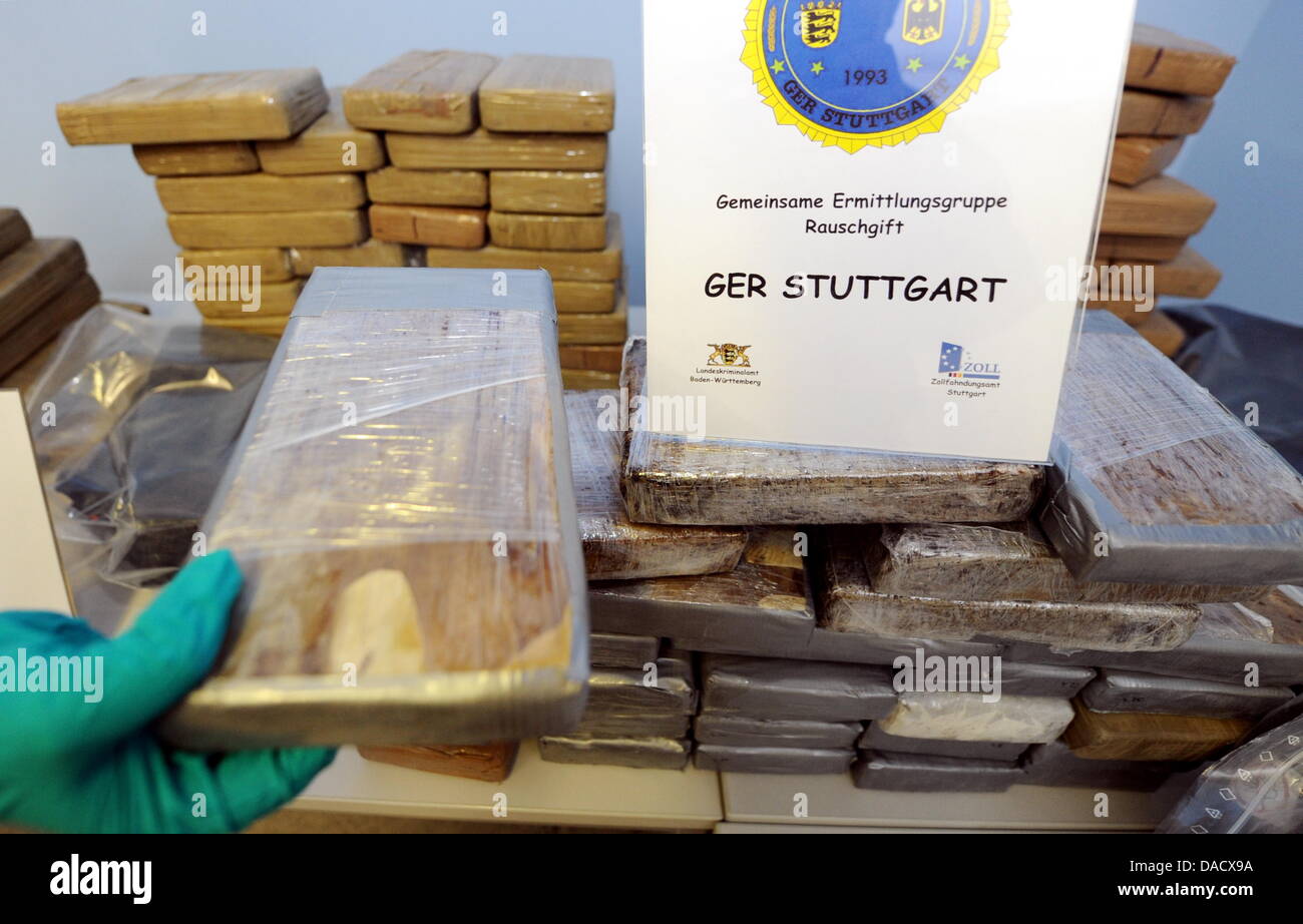 A hand holds a package of cocaine belonging to a drug find of 130 ...