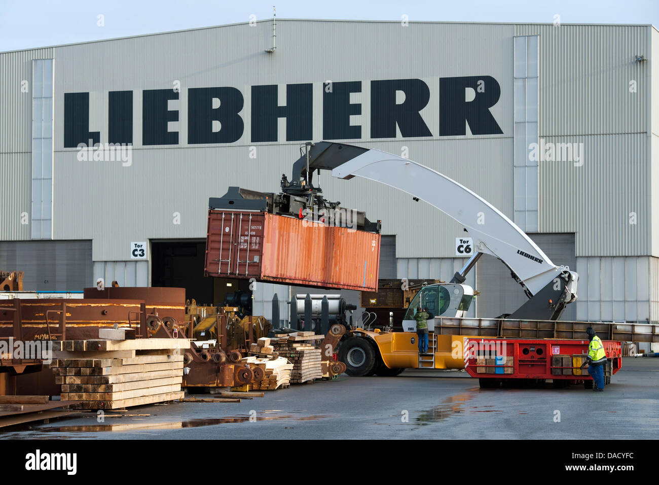 A reach stacker unloads a shipping container at the factory premises of ...