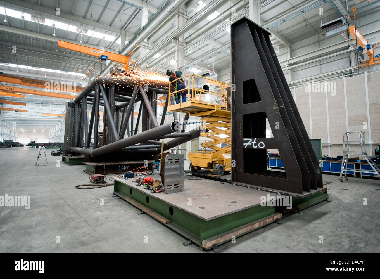 An employee welds a steel element at a factory of equipment ...