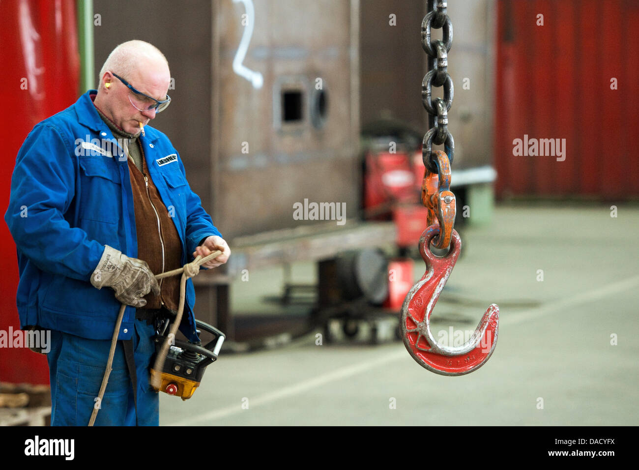 An employee operates a crane at a factory of equipment manufacturer ...