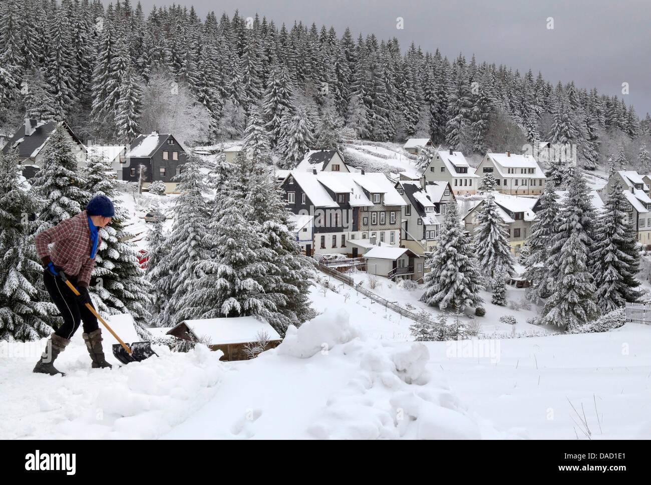 A woman shovels snow in the snow-covered village of Stuetzerbach ...