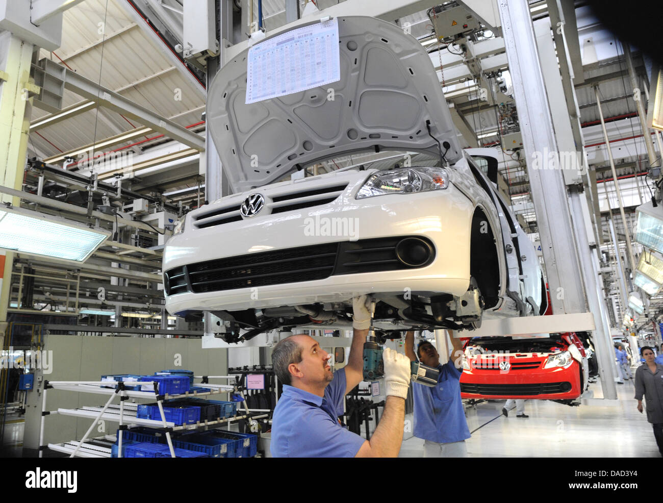Workers stand underneath a VW Gol on the assembly line at the ...