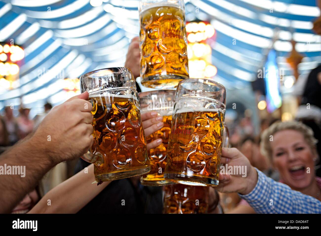 Visitors to the Cannstatter Volksfest toast beer mugs in a festival ...