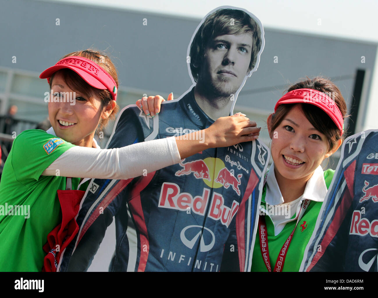 Japanese girls pose next to a stand up of German Formula One driver ...