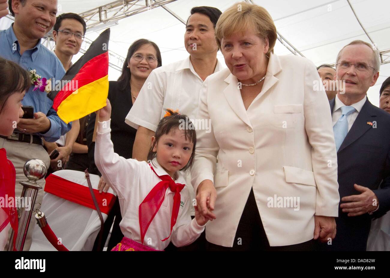 German Chancellor Angela Merkel is welcomed by a small Vietnamese girl ...