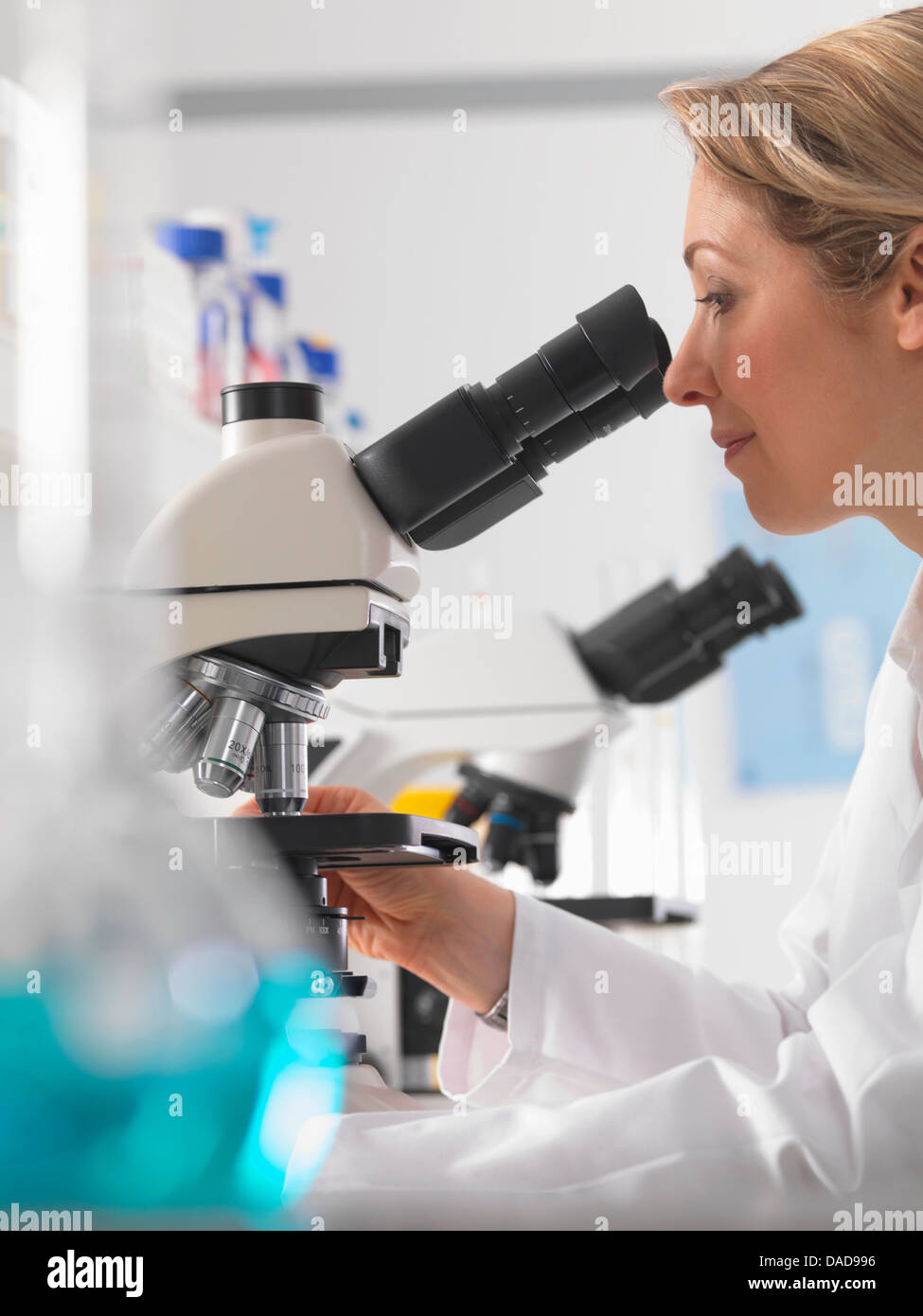 Female microbiologist viewing specimen under microscope in lab Stock ...