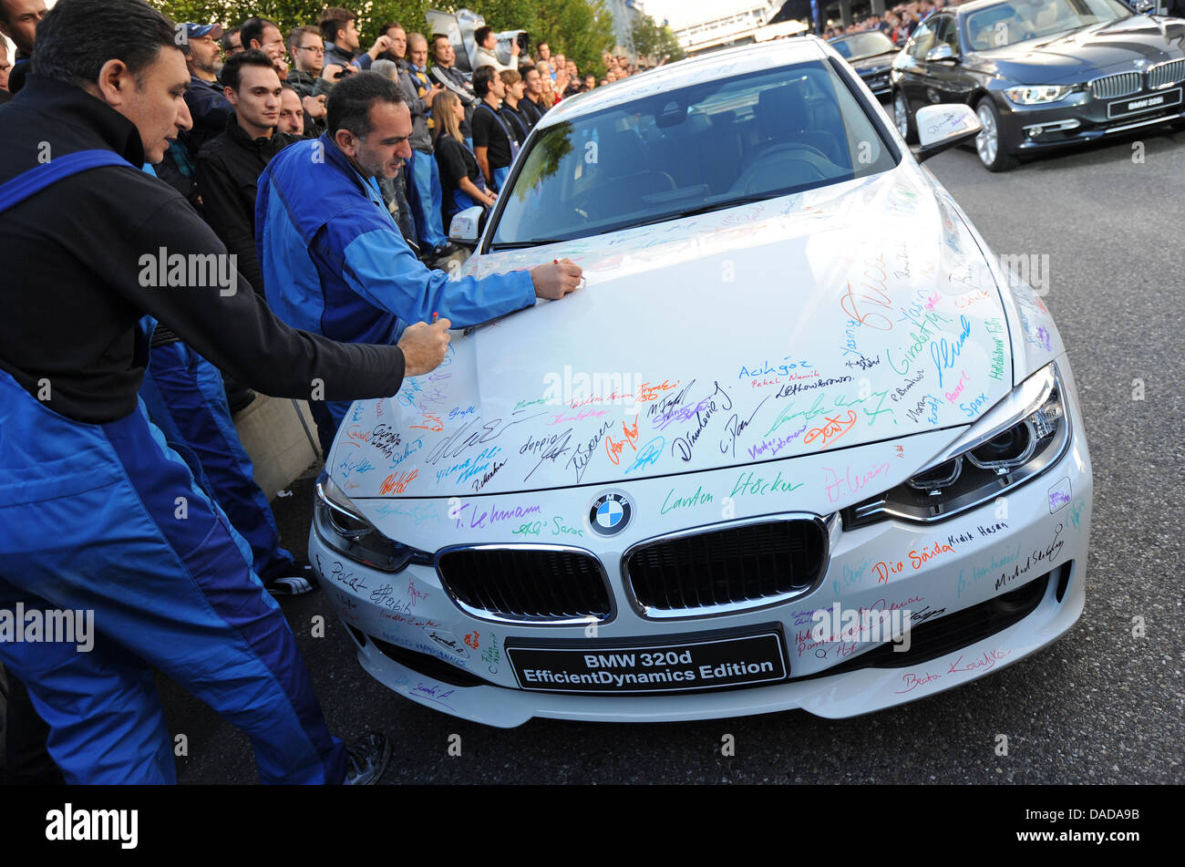 BMW employees sign a BMW 320d during the presentation of the new BMW 3 ...