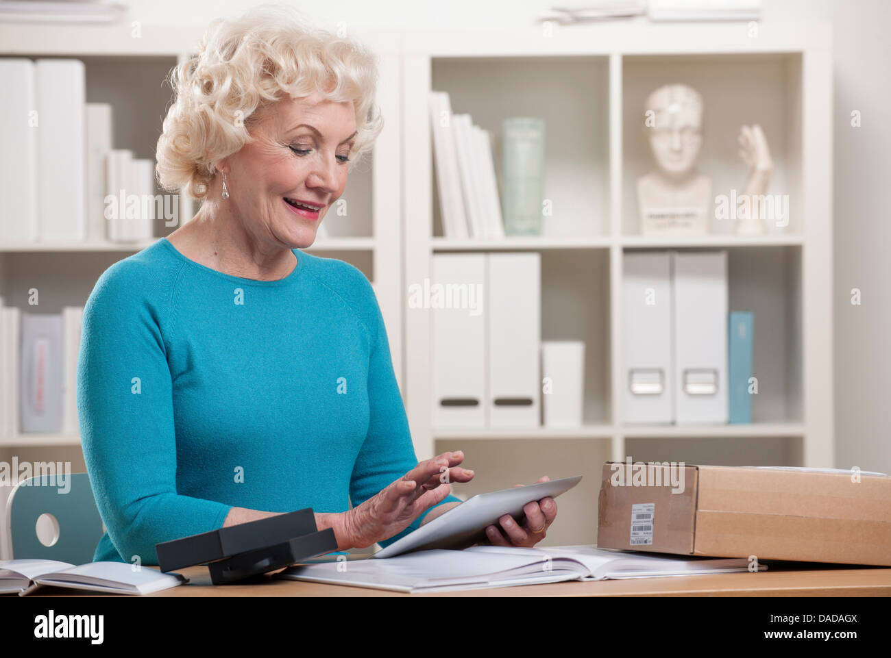 Senior woman using digital tablet while having coffee on bed at home ...