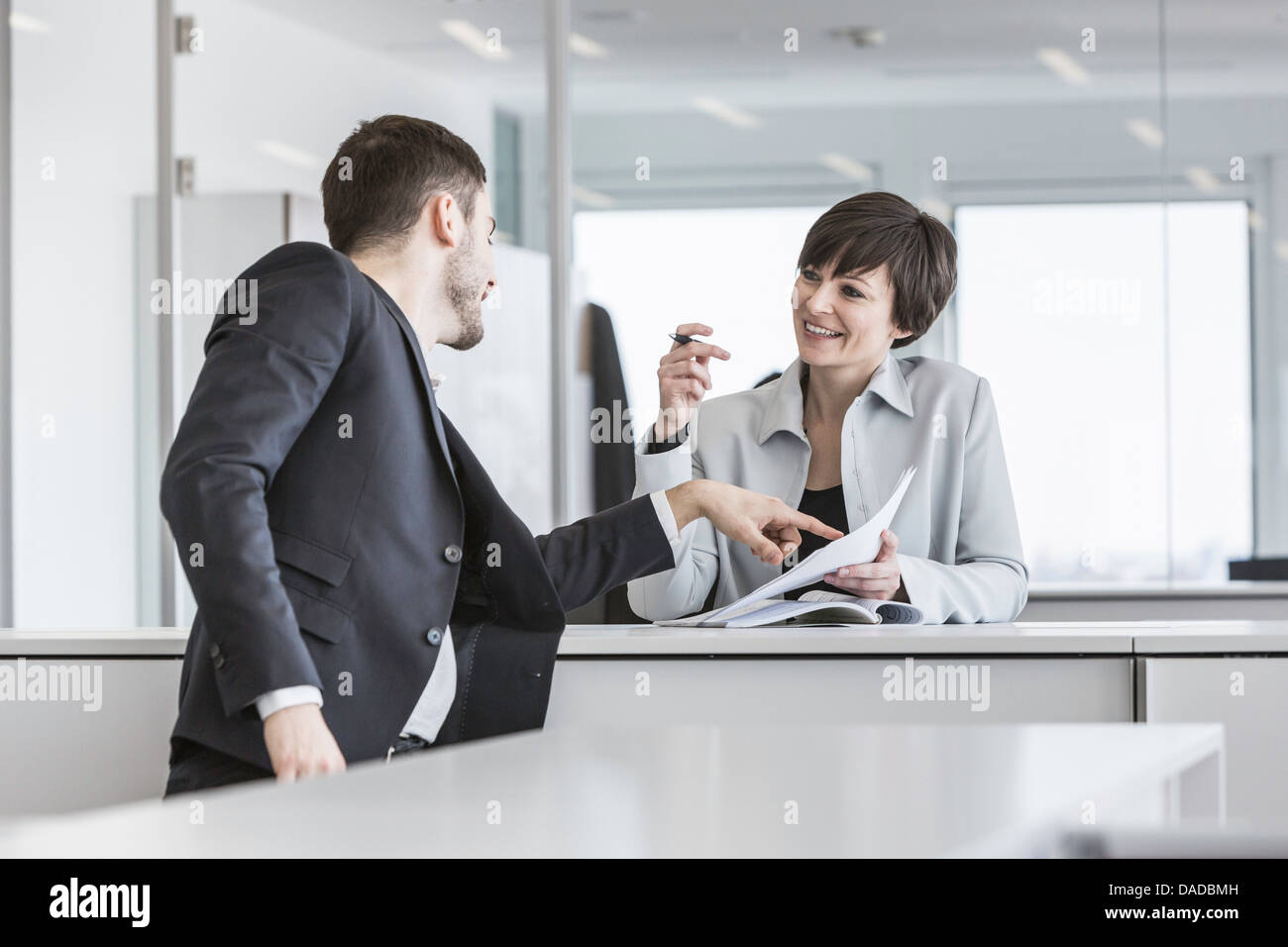 Businesspeople standing doing paperwork in office Stock Photo - Alamy