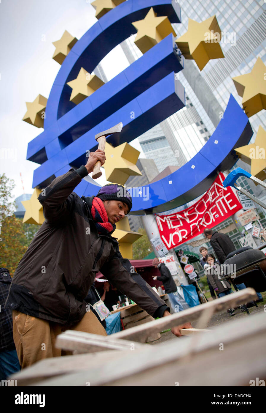 An activist cuts wood underneath a Euro sign in front of the European ...
