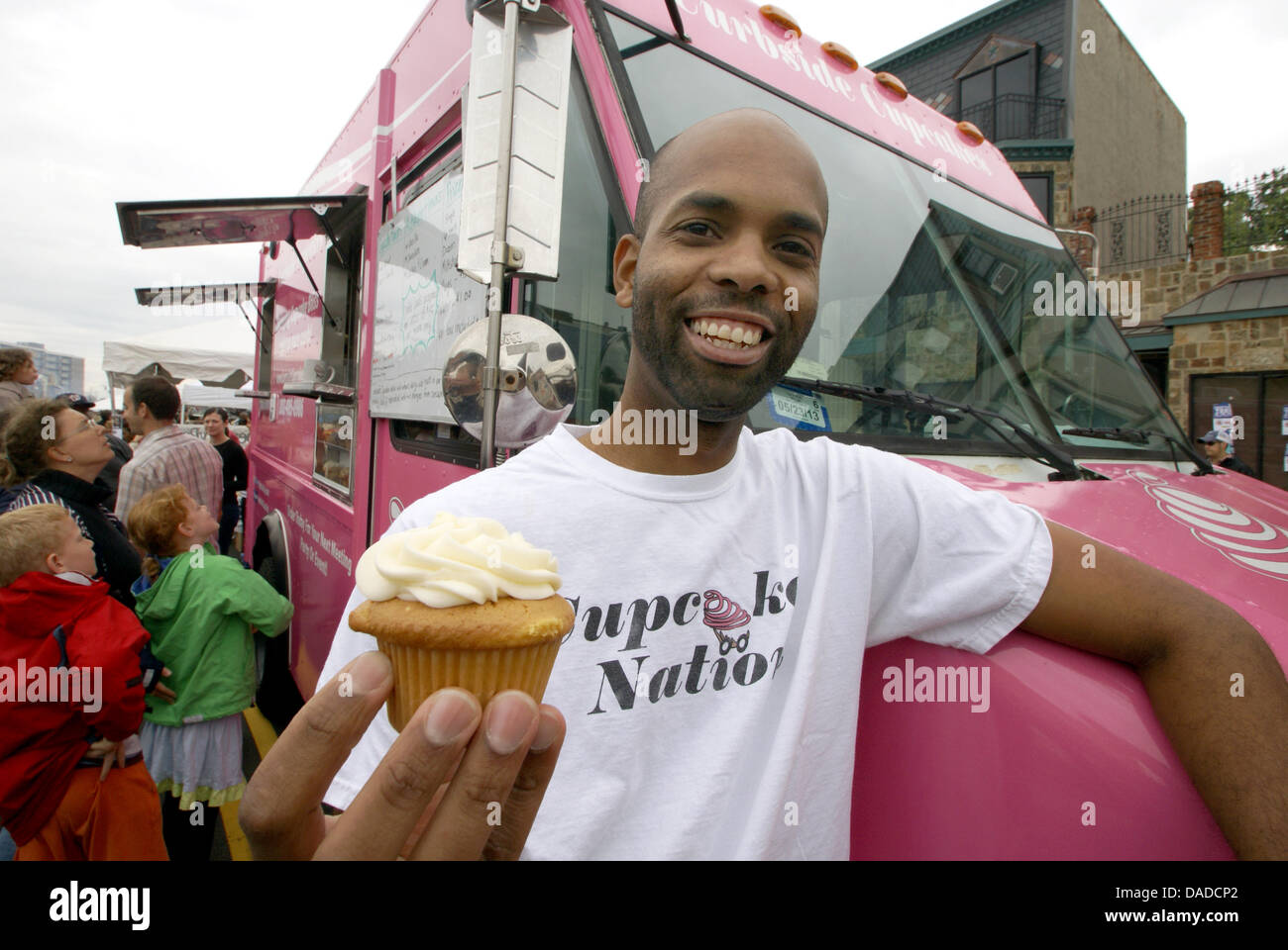 Sam Whitfield, owner of the Curbside Cupcakes Truck, presents one of ...