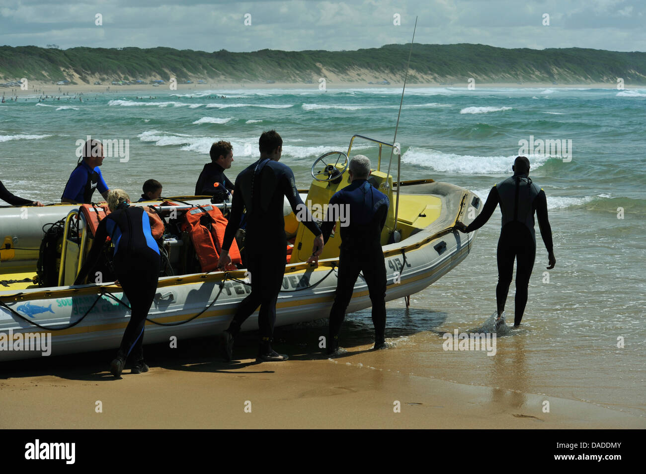 Scuba divers dragging Rigid Inflatable Boat into water for reef diving ...
