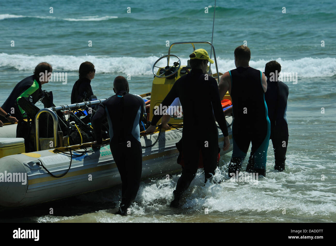 View of recreational Scuba Divers dragging RIB into surf at Sodwana Bay ...