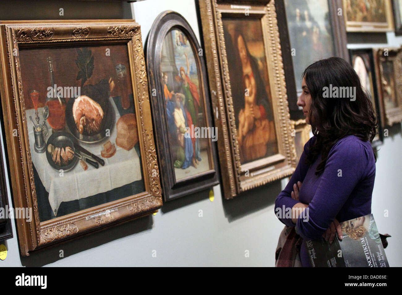 A woman looks at the painting "Still Life with Ham and Glass Bottle" by ...