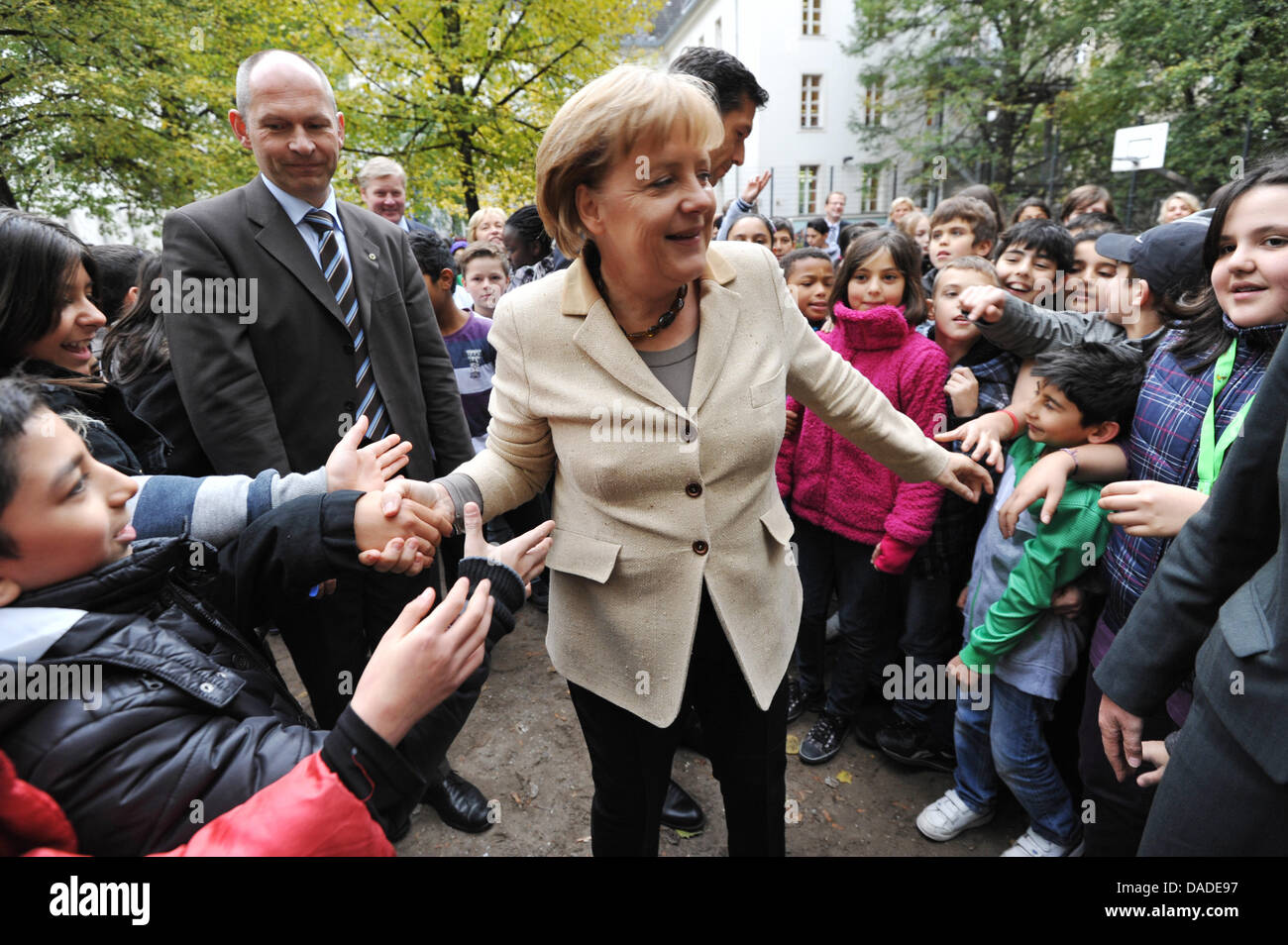German Chancellor Angela Merkel is greeted by pupils of Erika Mann ...