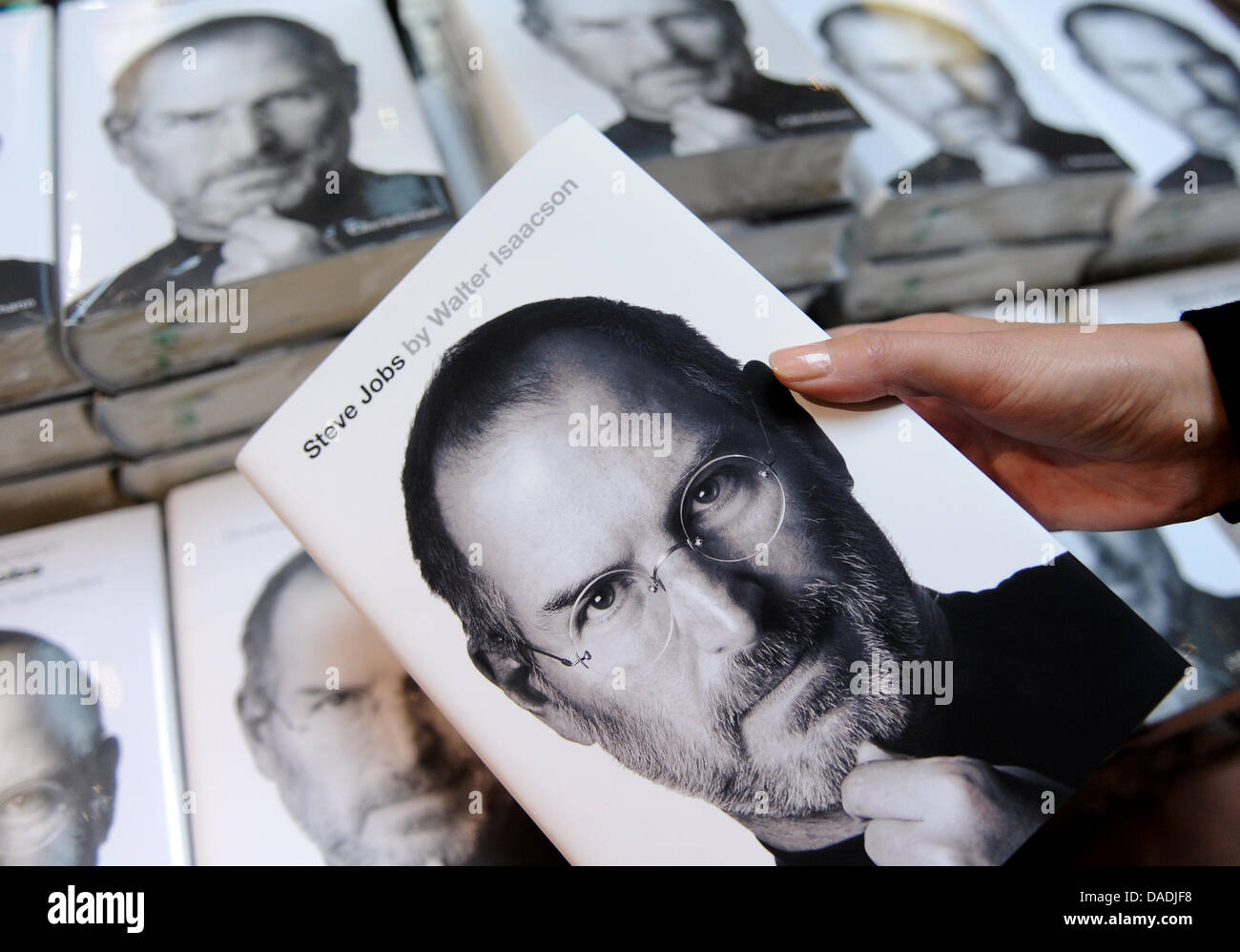 A hand holds the biography of the founder of Apple, Steve Jobs, at ...