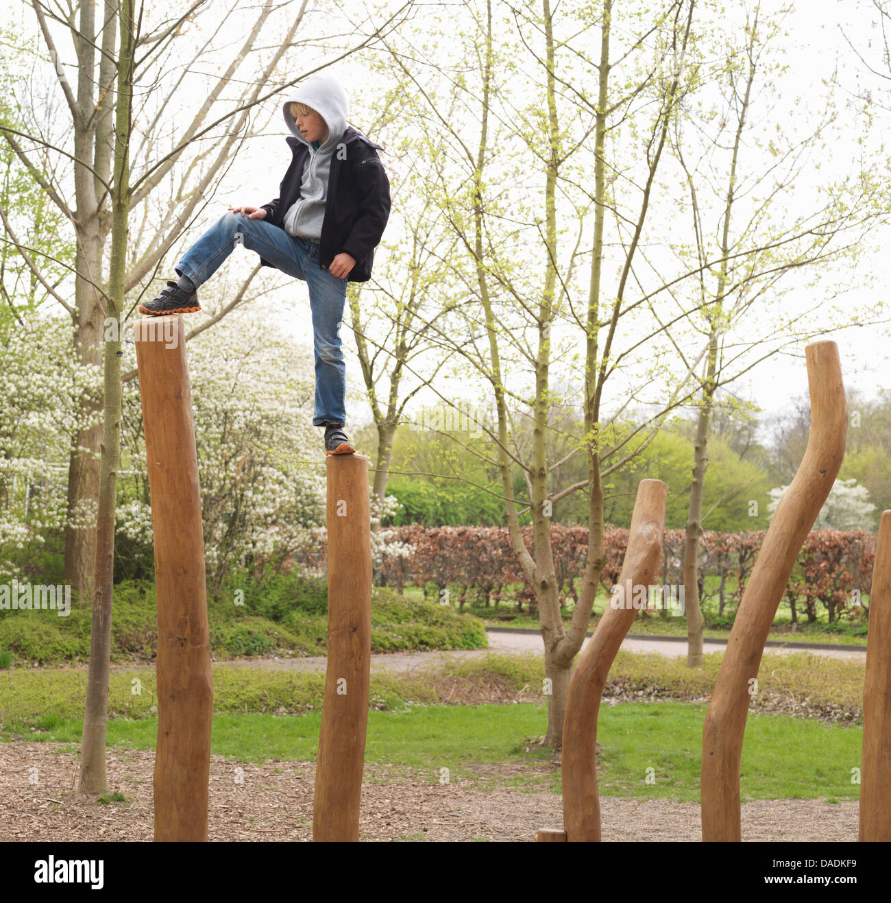 Boy stepping on wooden posts in park Stock Photo - Alamy