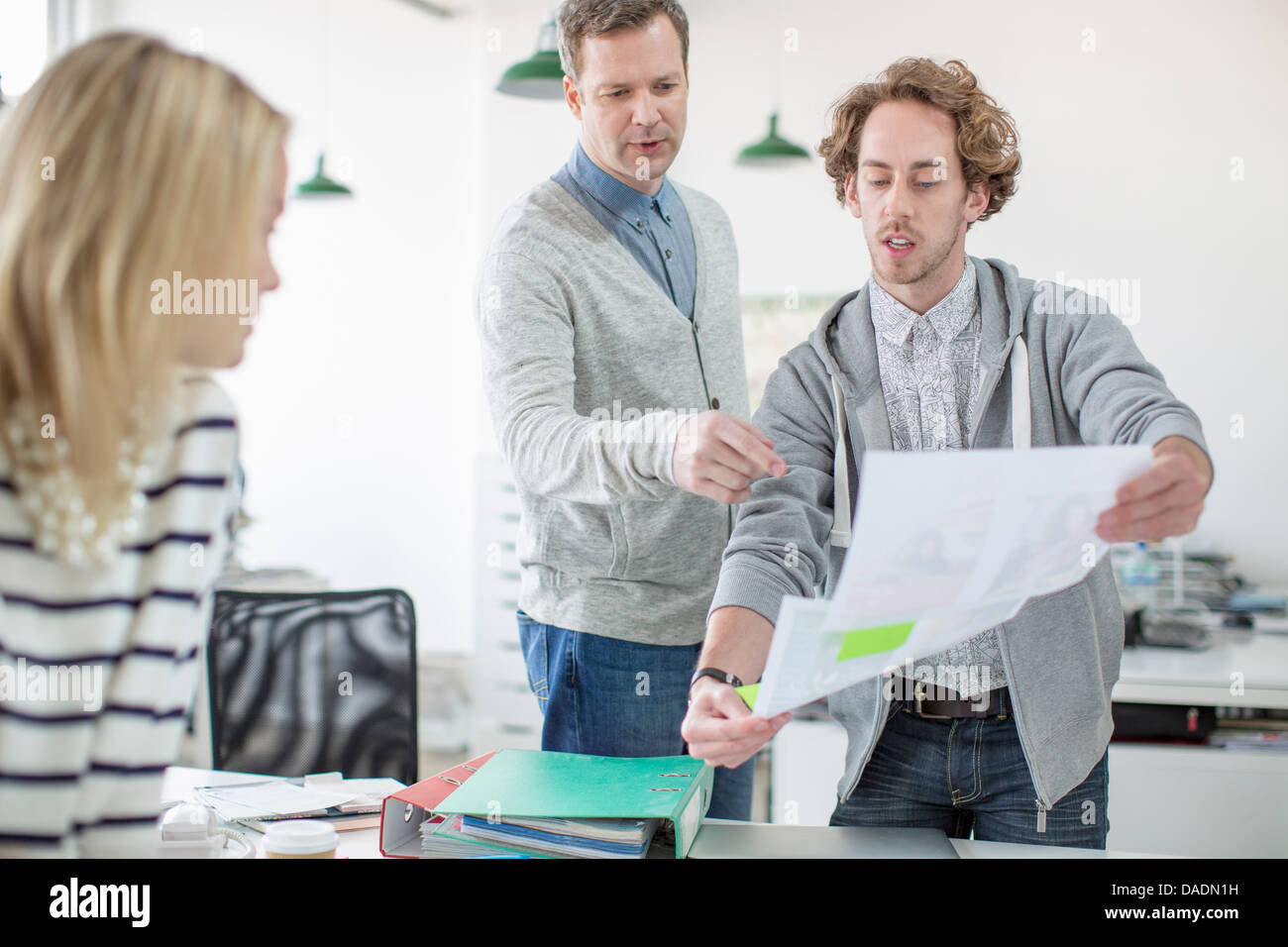 Young man showing plans to colleagues on meeting in creative office ...