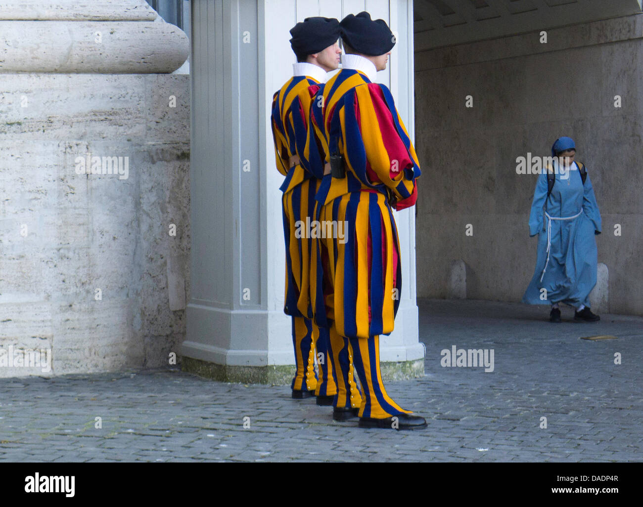 Two Swiss Guards in traditional uniforms watch a nun walk by in Vatican ...