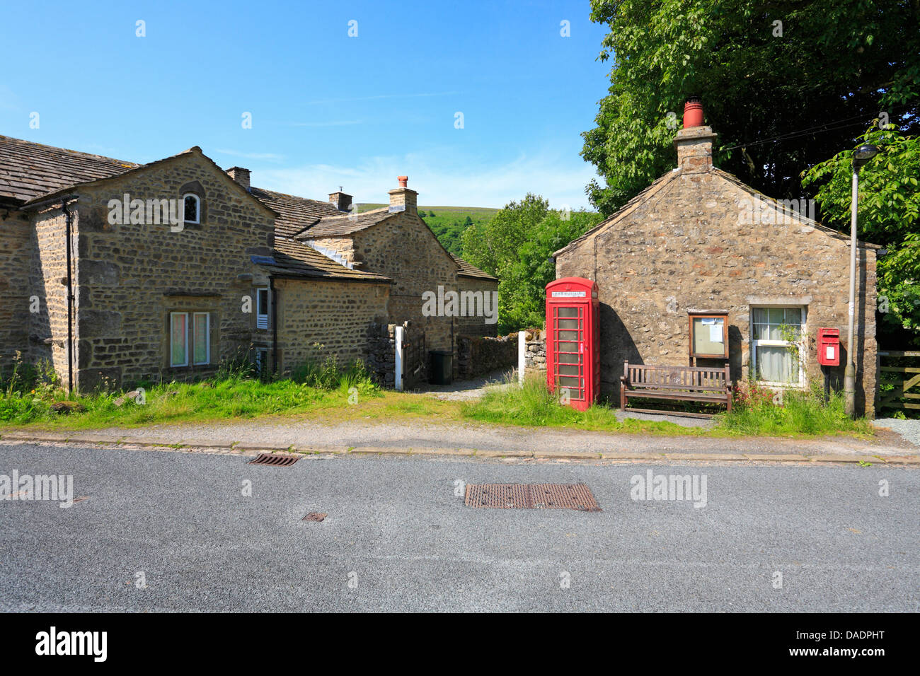 Telephone box, post box, notice board and bench by a stone cottage ...