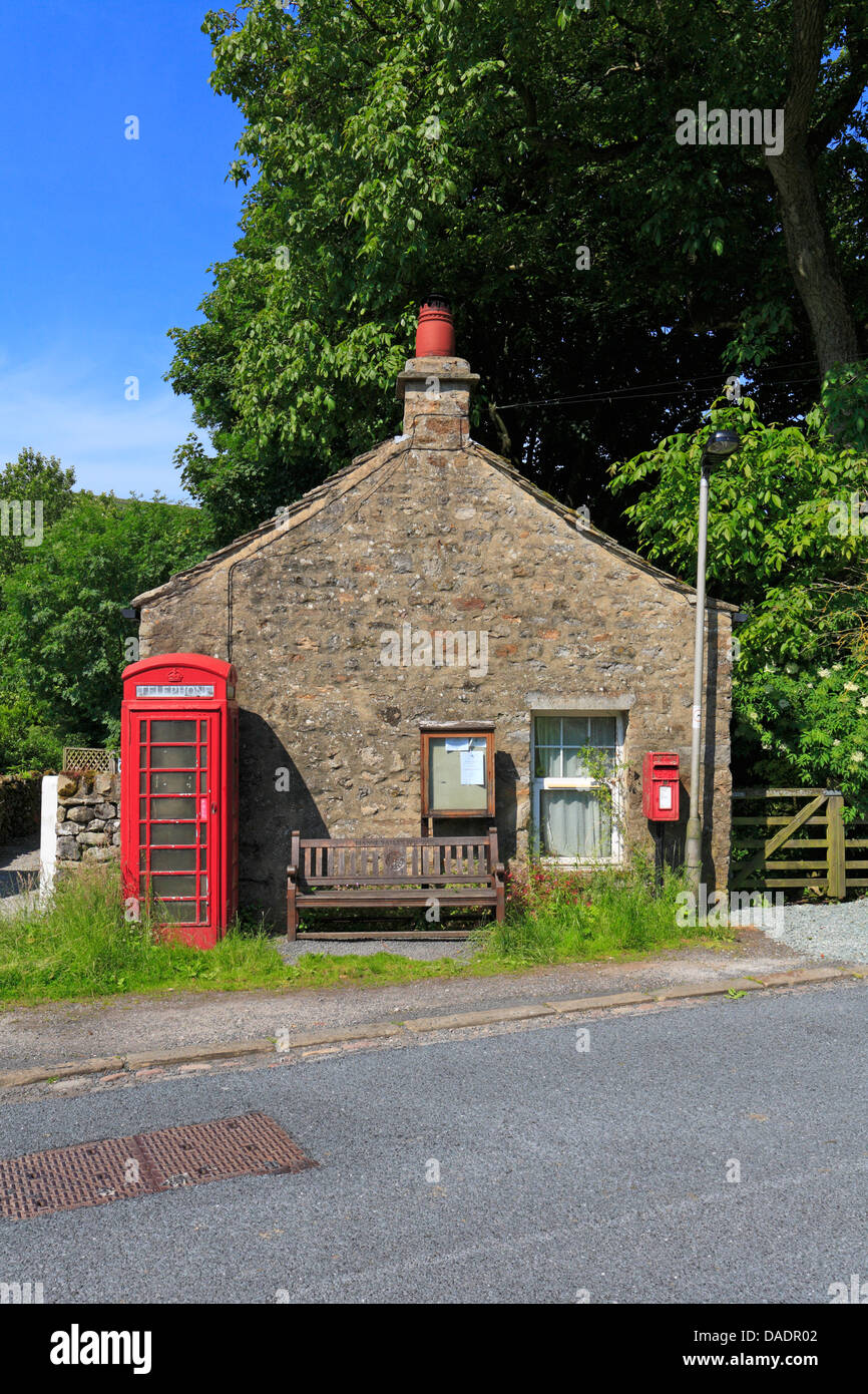 Telephone box, post box, notice board and bench by a stone cottage ...