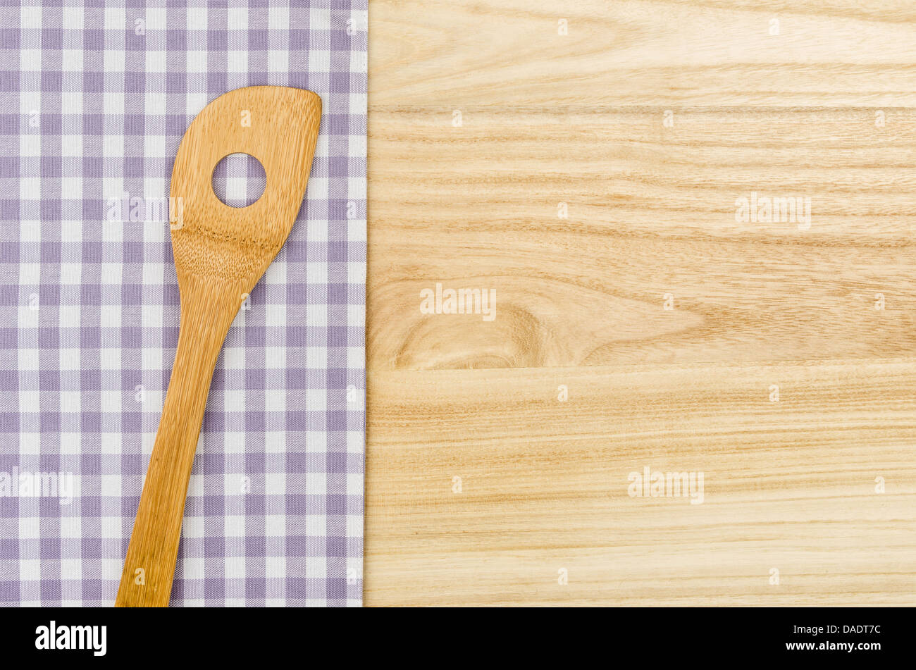 Wooden spoon on a purple checkered table cloth on a wooden background ...