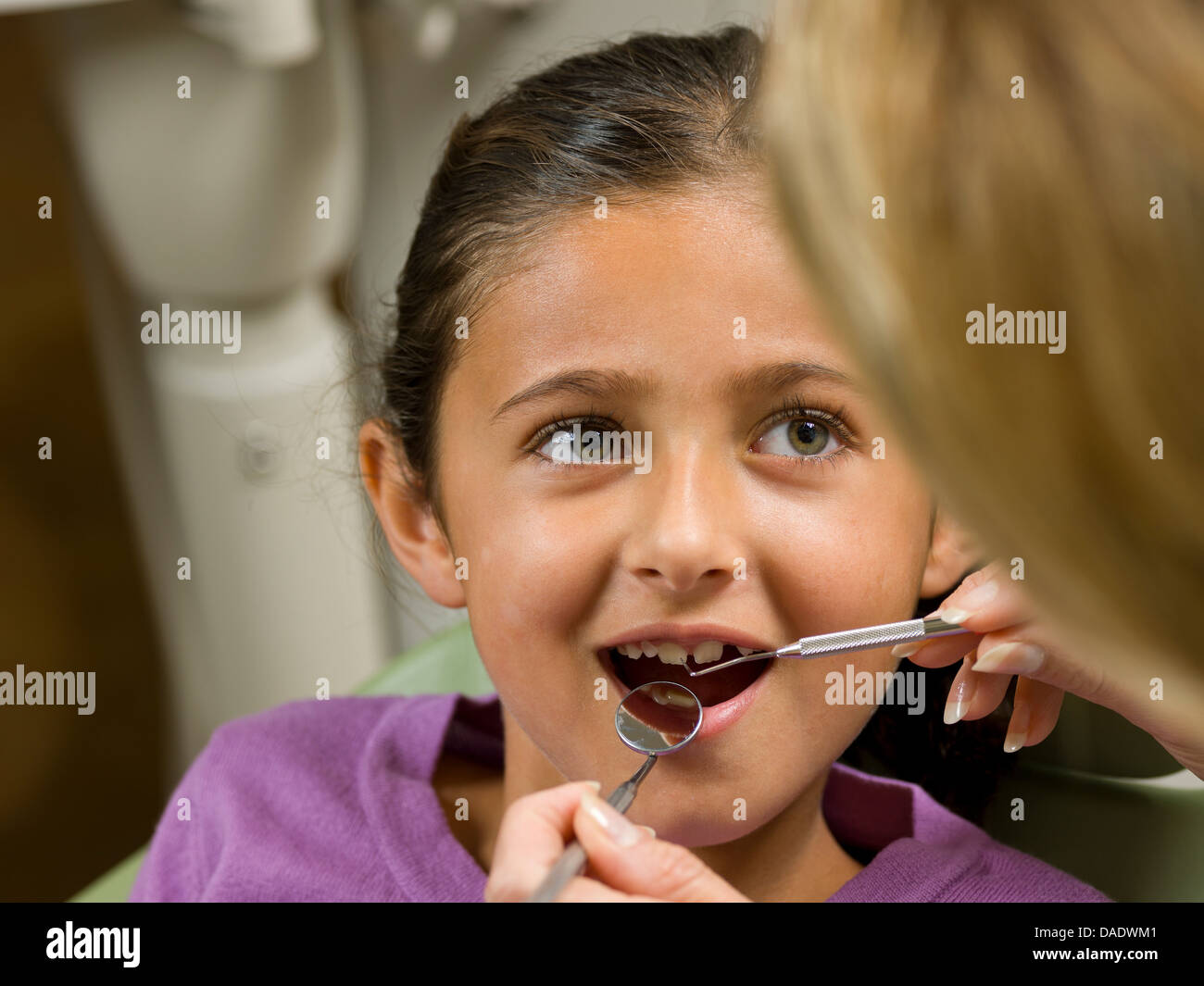Dentist looking at young girl's teeth Stock Photo - Alamy