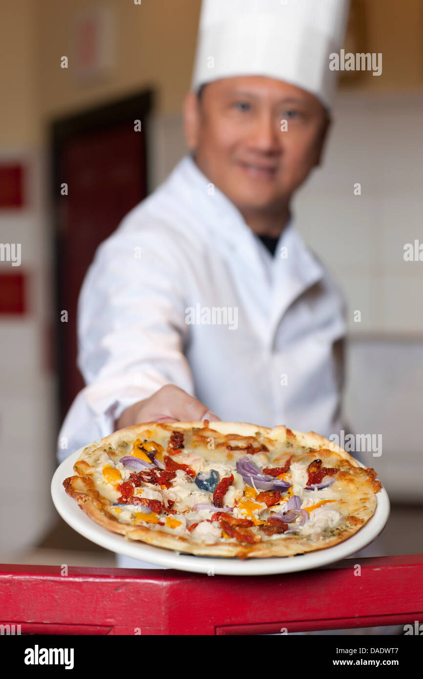 Mature chef holding fresh pizza on plate, portrait Stock Photo - Alamy