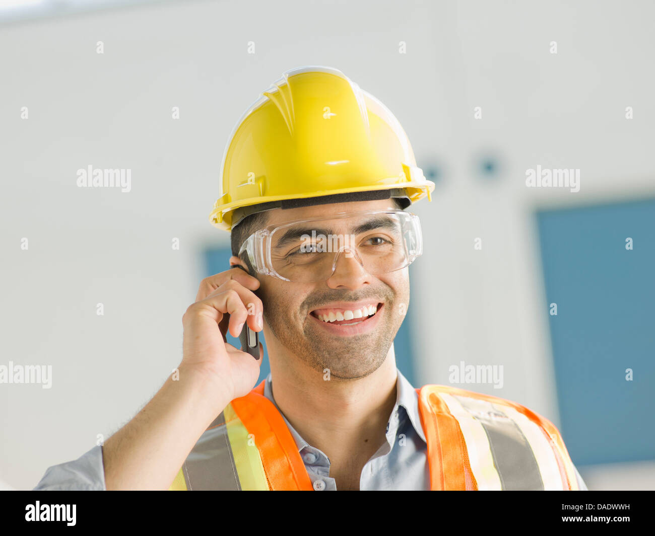 Mid adult construction worker using mobile phone, smiling Stock Photo ...