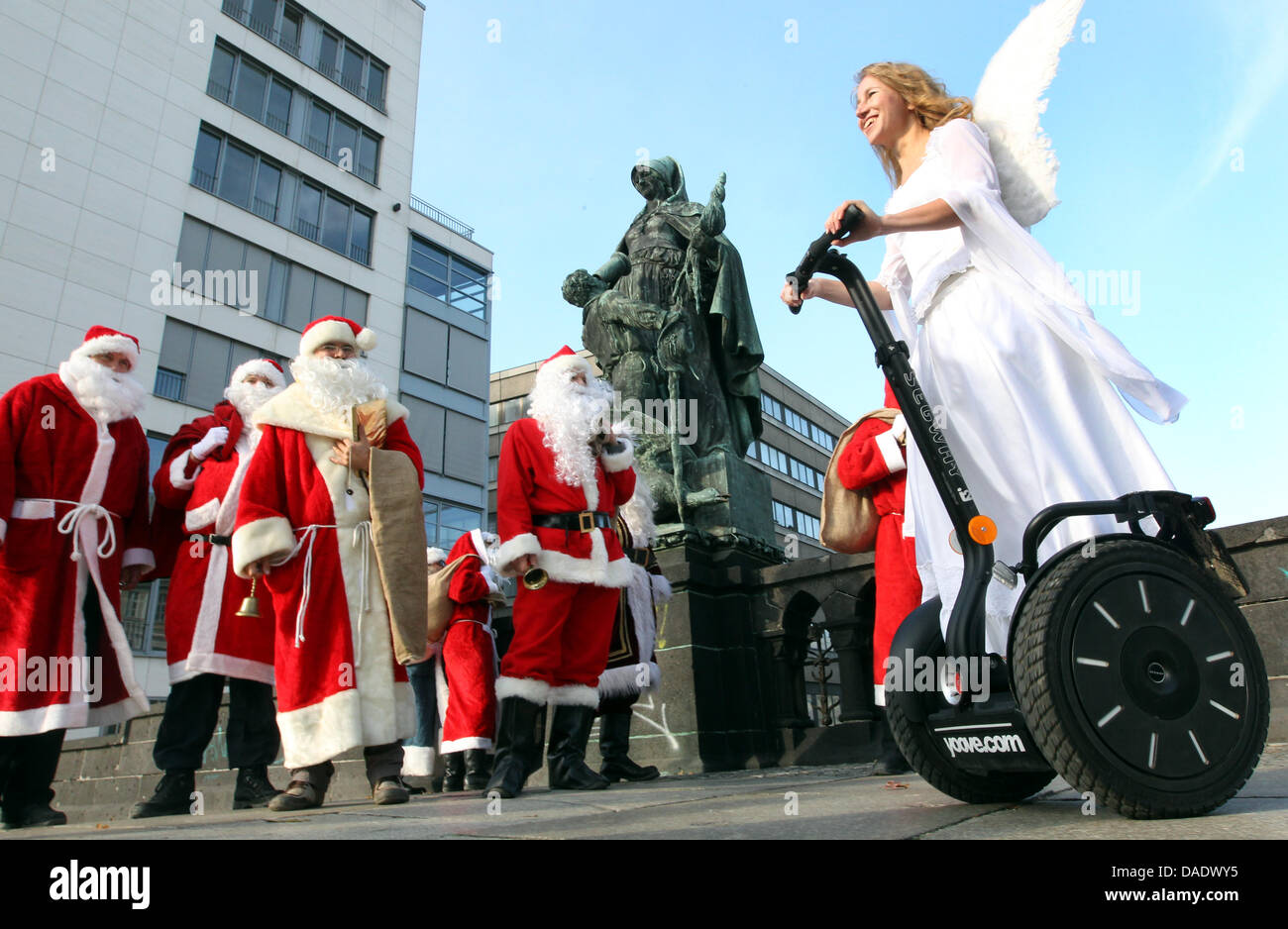 A christmas angel on a Segway drives past some Santa Clauses in Berlin ...