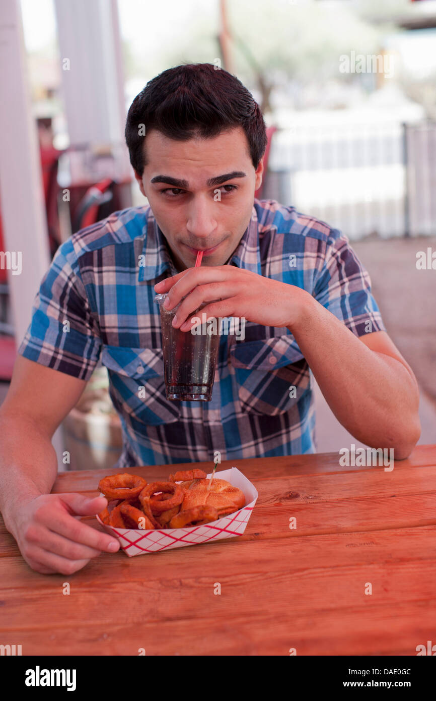 Young man drinking cola in diner, looking away Stock Photo - Alamy