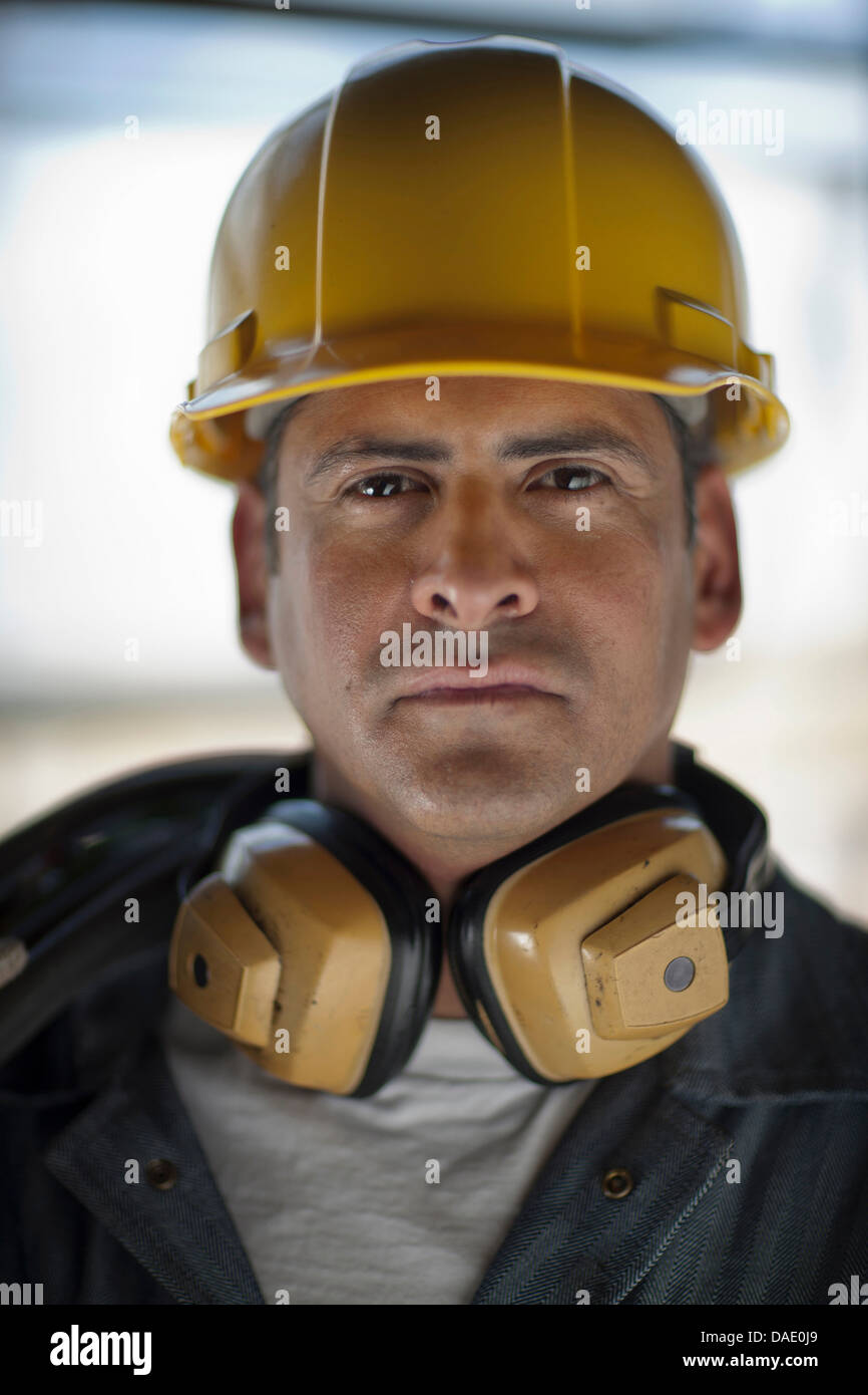 Mature construction worker wearing hard hat and ear defenders Stock ...