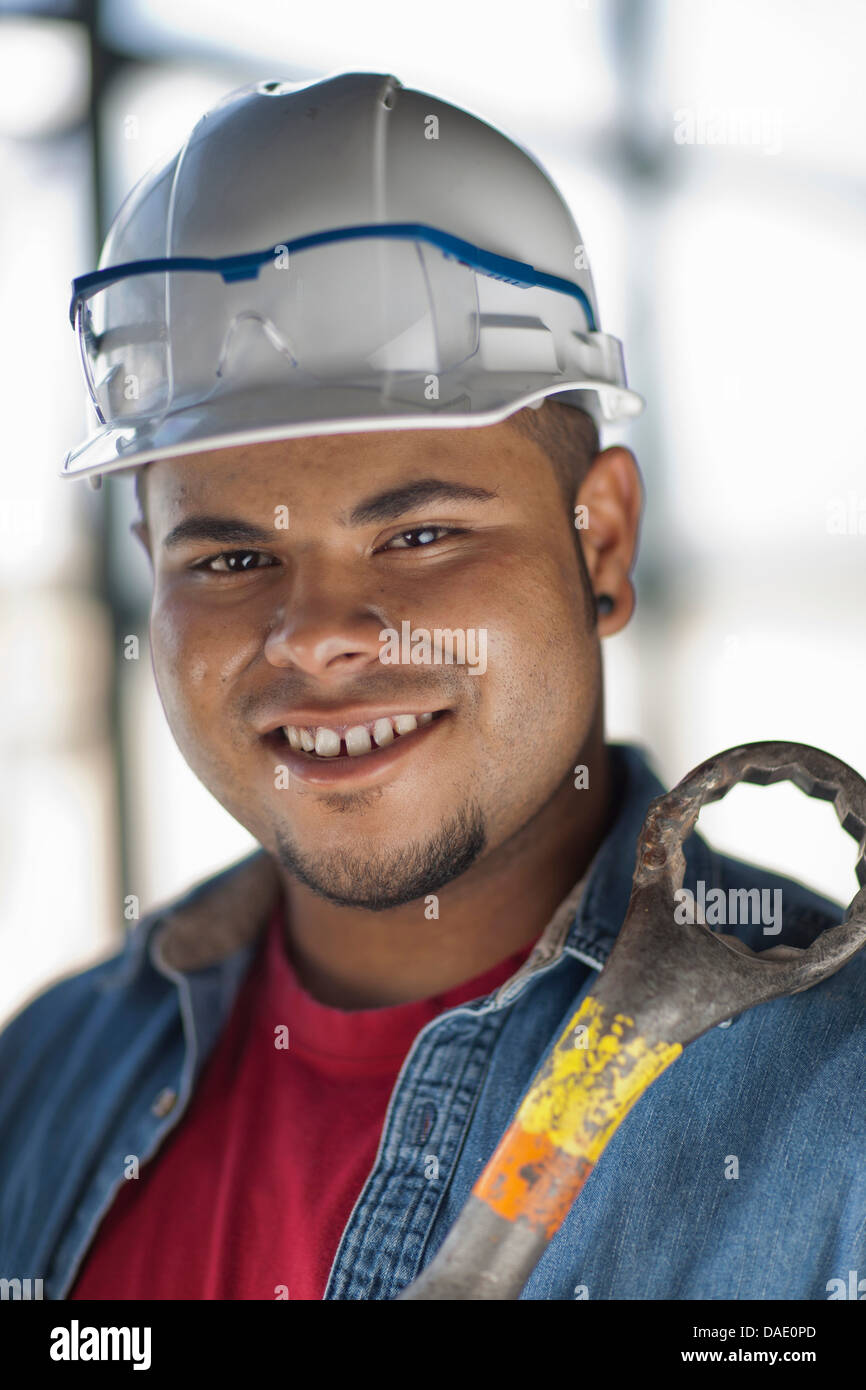 Young construction worker wearing hard hat and holding wrench, smiling ...